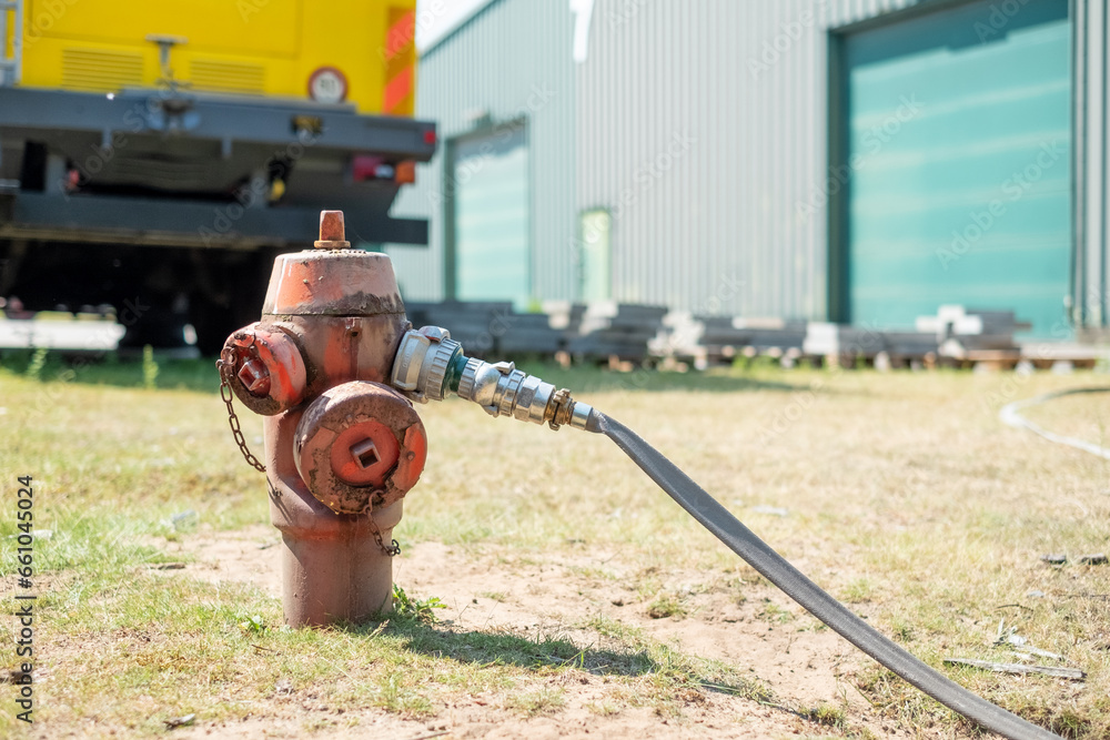 An aged red fire hydrant with an attached hose stands as an iconic ...