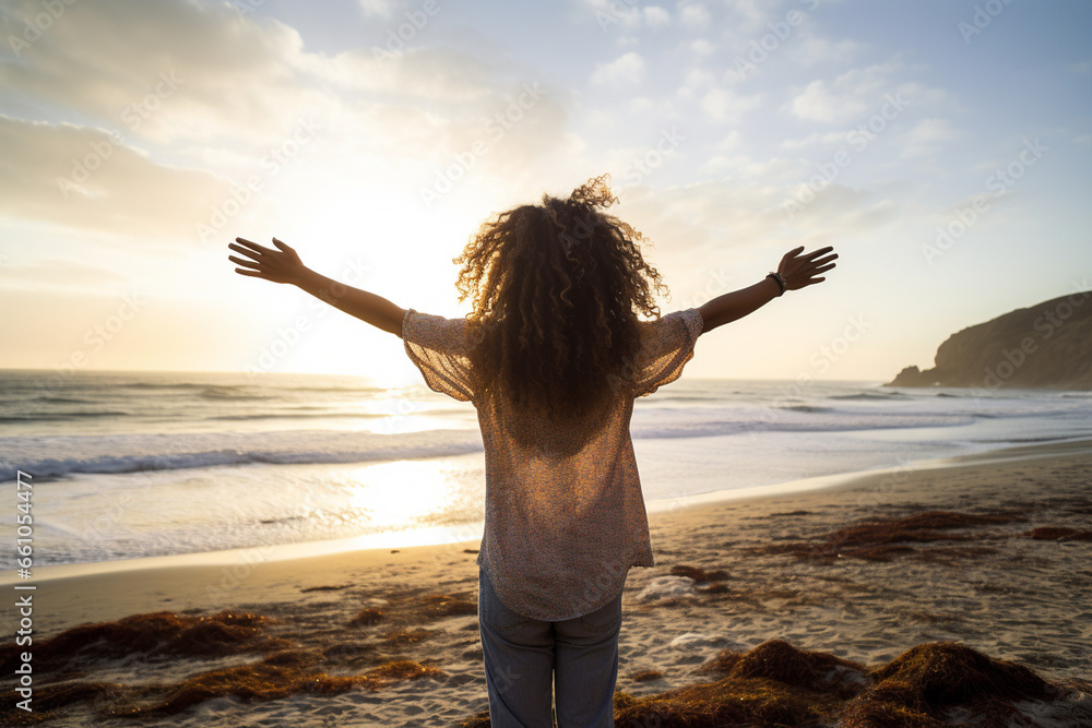 At a peaceful beach, a woman raises her arms in a powerful pose, her ...