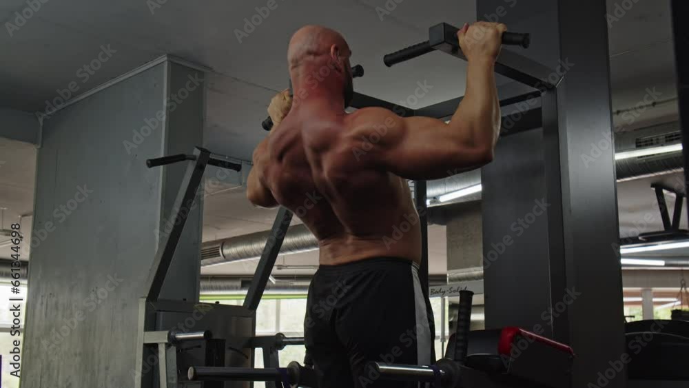 Young man bodybuilder is doing pull up in the gym on the horizontal bar ...