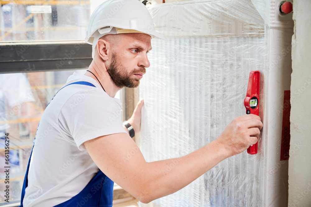 Male plumber in safety construction helmet using spirit level tool ...