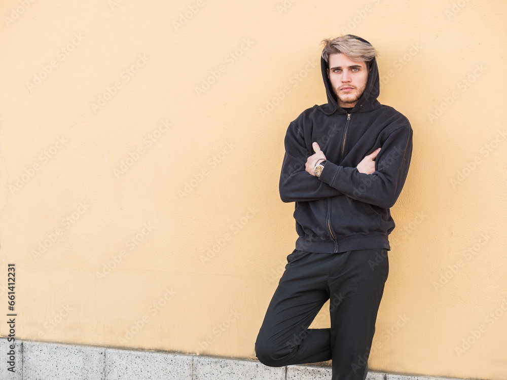 A man leaning against a wall with his arms crossed. Photo of a man with ...