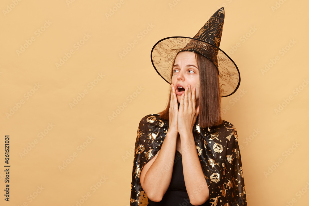 Shocked scared woman wearing witch costume and cone hat isolated over ...