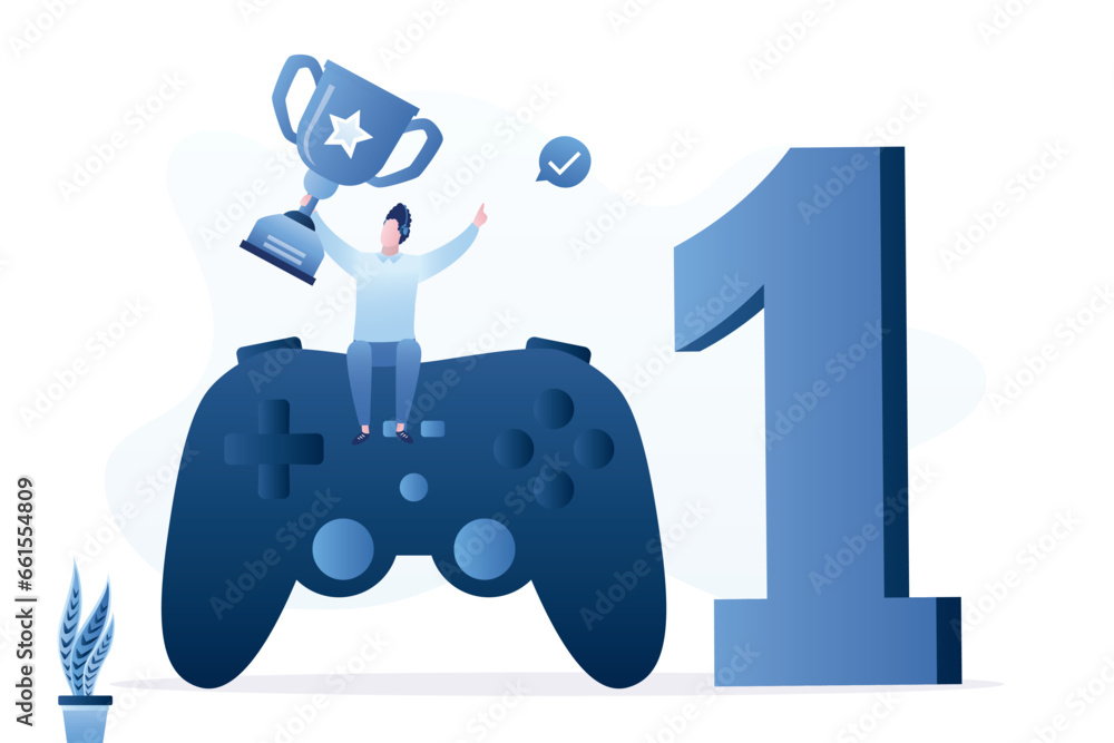 Happy gamer sitting on big joystick and holds winner cup. First place ...