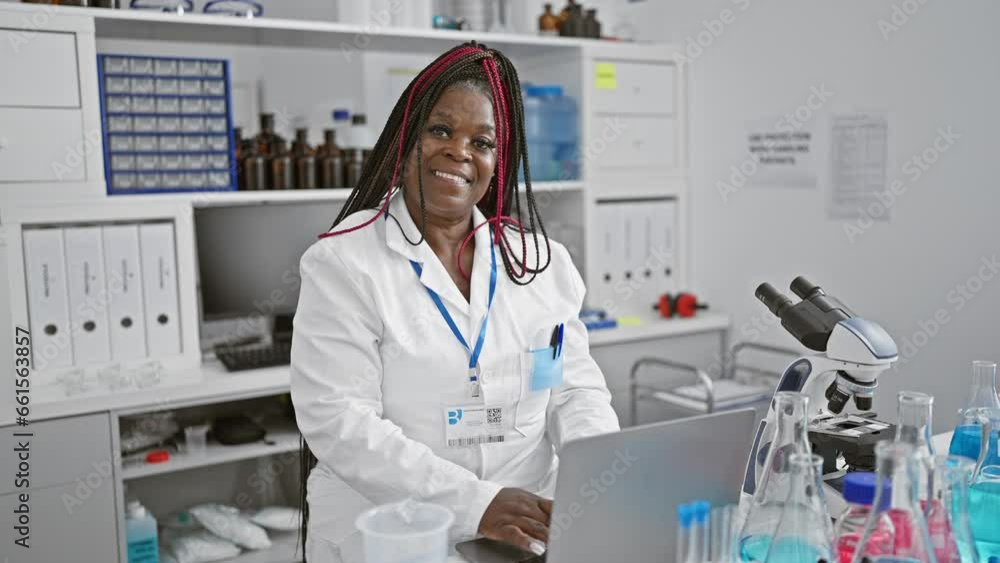 Confident african american woman, smiling widely, fully immersed in scientific research on her ...