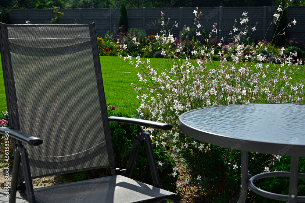 metalowy fotel i szklany stolik w ogrodzie, kącik wypoczynkowy, metal ...