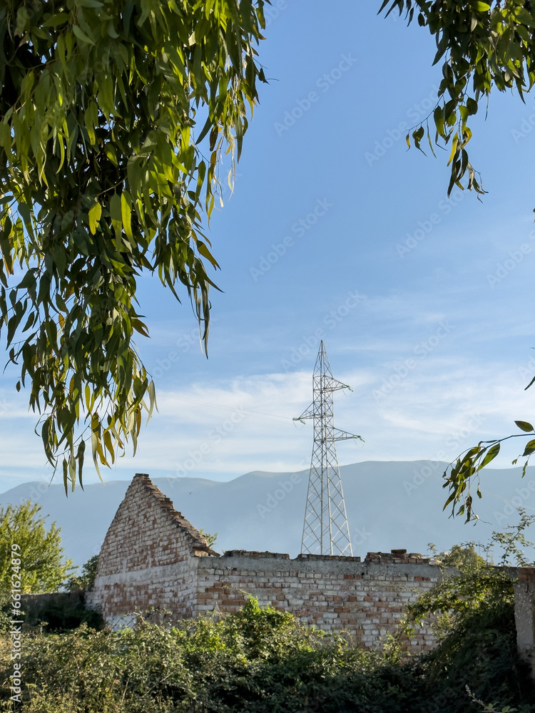 Overhead line pylon, high voltage pylon and ruins of a brick building ...