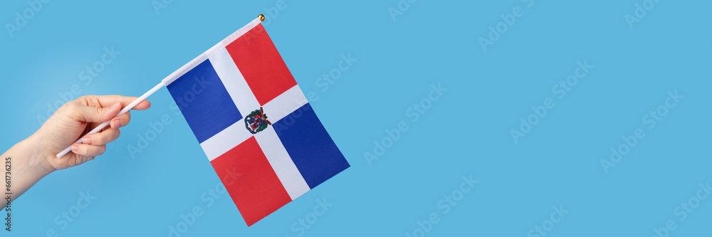 Dominican Republic flag in hand on a blue background, copy space ...