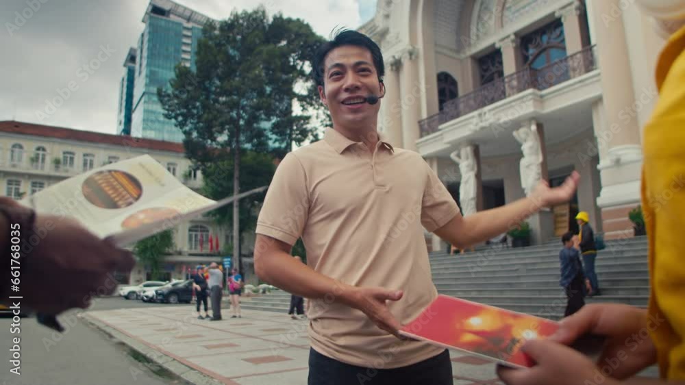 Medium shot of smiling Asian male travel guide standing in front of ...