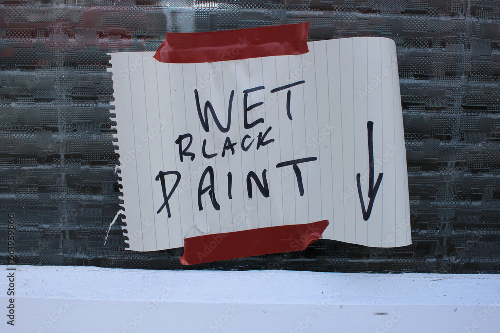Hand written sign "Wet black paint" with arrow pointing down attached ...