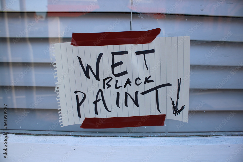 Hand written sign "Wet black paint" with arrow pointing down attached ...