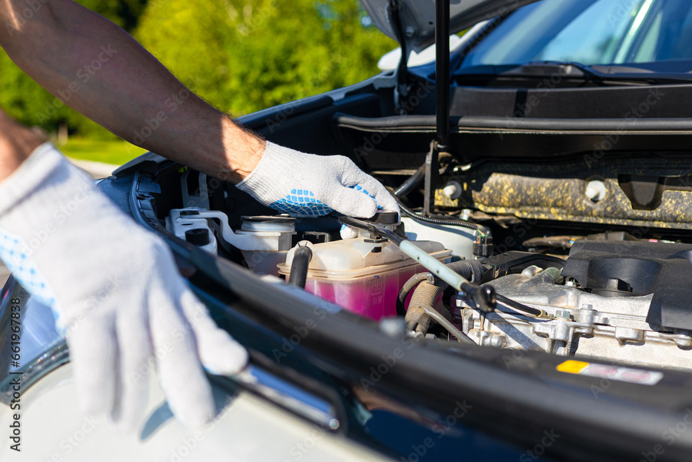 Driver check the coolant level in the engine compartment of the car ...