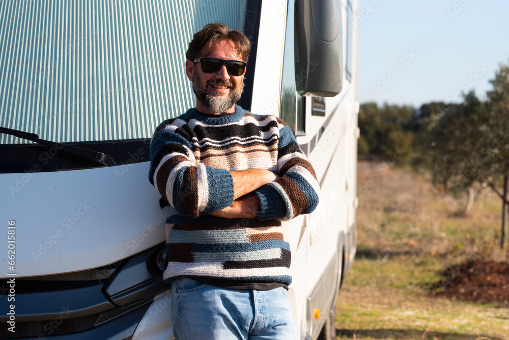 One man posing and smiling at the camera outside a new modern camper ...