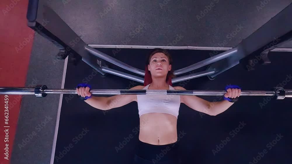 Woman in the gym trains on bodybuilding machines. A woman pumps her ...