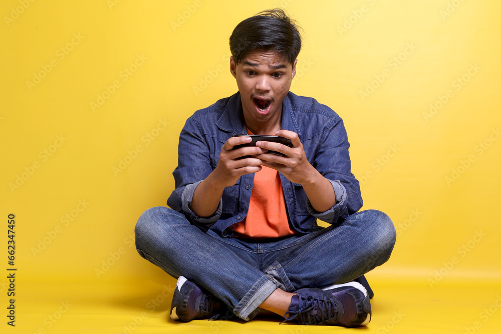 Young Asian Man Sitting Crossed Legs On Floor And Showing Shocked