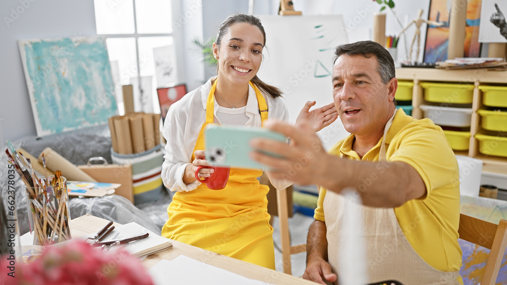 Smiling male and female artists, sipping coffee and talking art, deeply ...