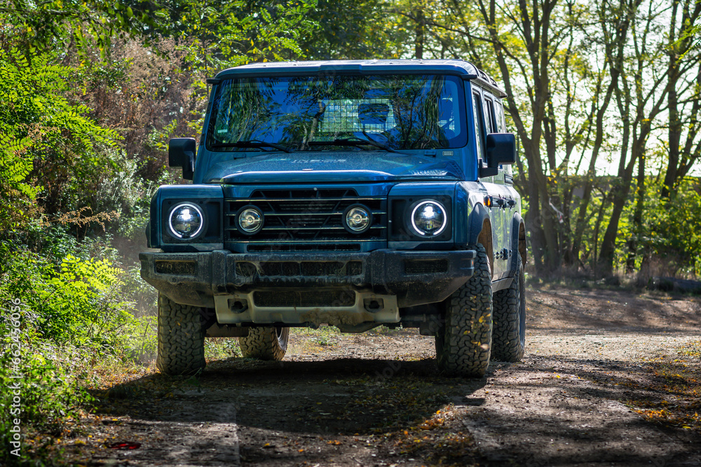 Ineos Grenadier all-terrain vehicle in blue one in the forest on a dirt ...