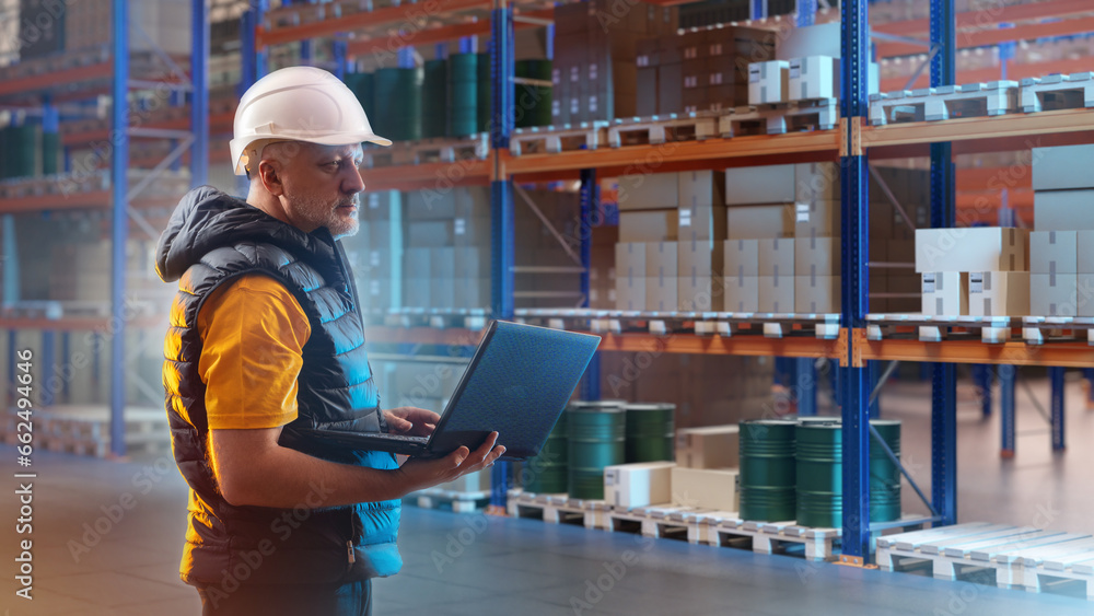 Man inside factory warehouse. Storekeeper stands with laptop. Storage ...