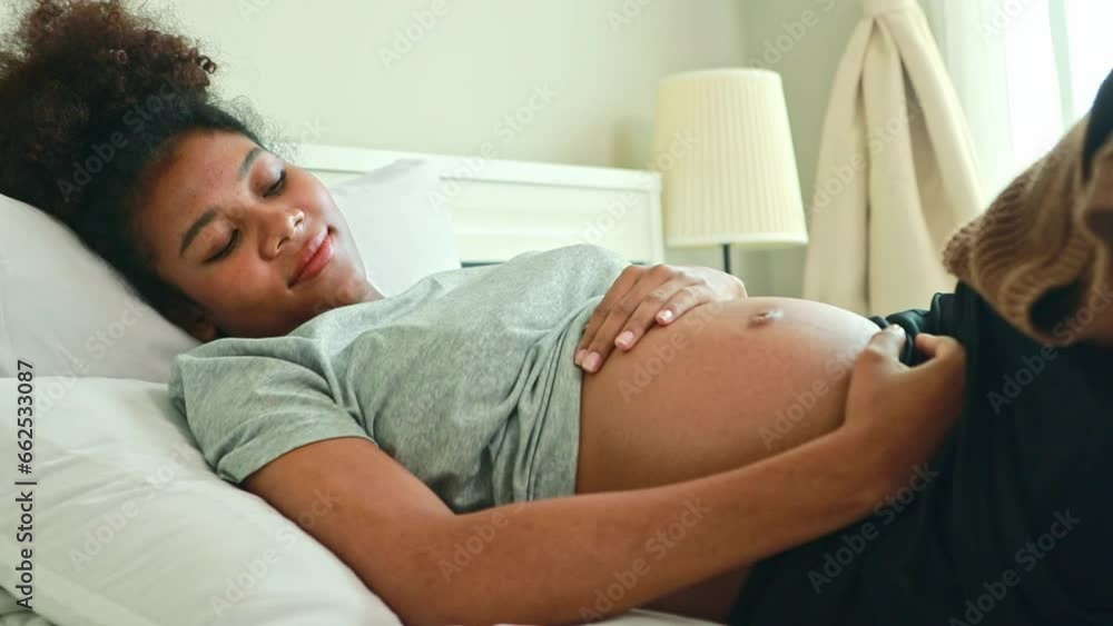 Happy portrait pregnant african american mother lying in bed looking at ...
