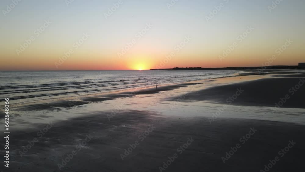 Drone over the beach with a dim light, you can see the sun, the sea ...