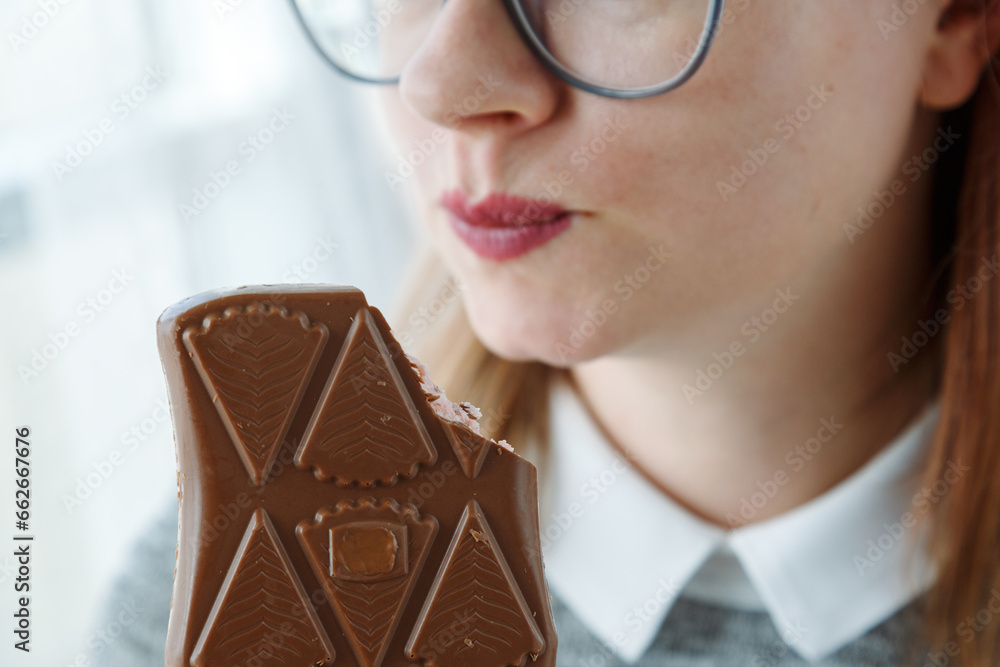 Young woman student eating bar of chocolate, close up of eating mouth ...