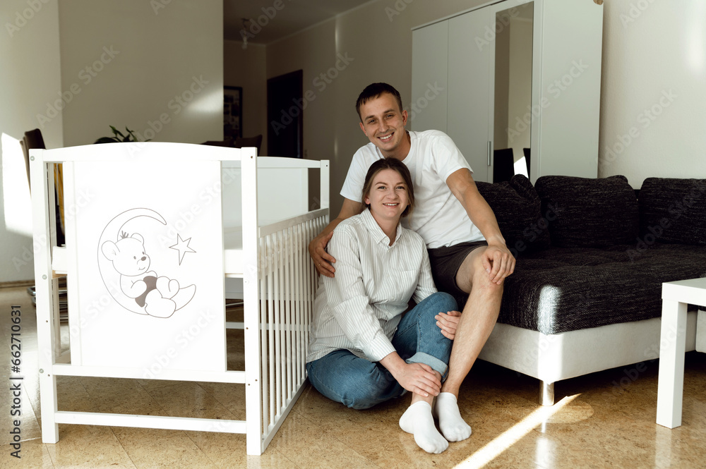 happy middle-aged pregnant couple sitting next to a baby crib. pregnant ...