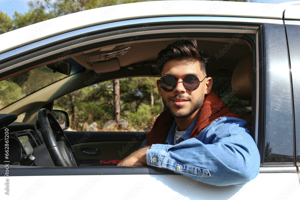 Young carefree man wearing a denim shirt looking out of the window of ...