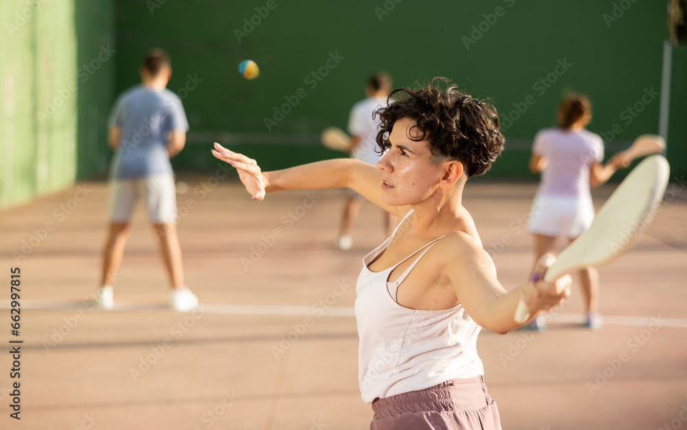 Latin woman serving ball with paleta during Basque pelota game outdoors ...