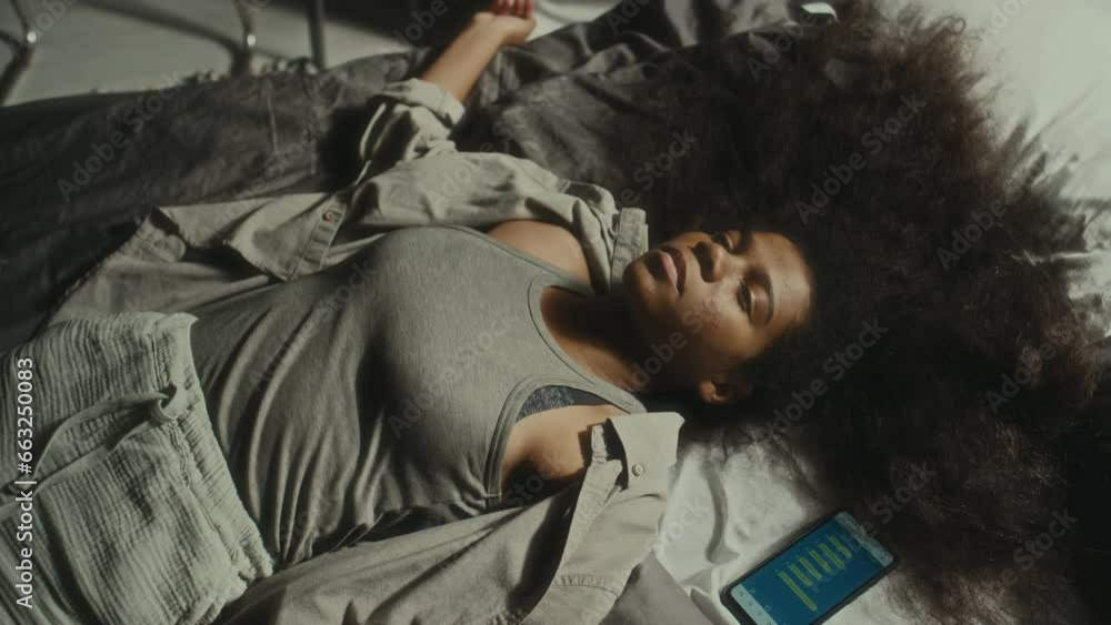 High angle shot of African American teen girl falling down on her bed ...