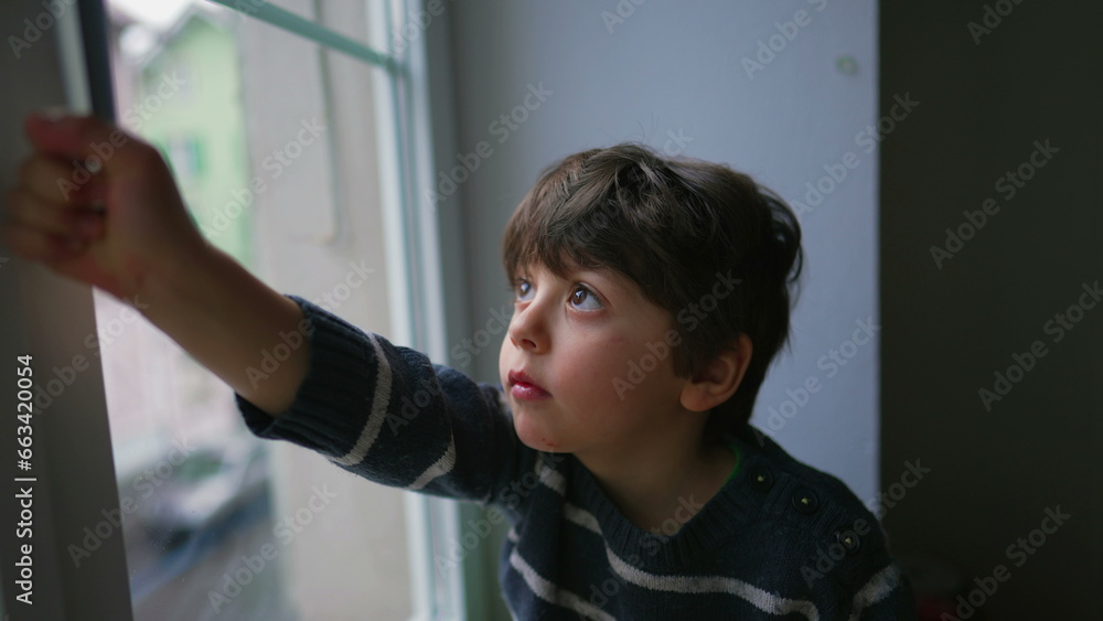 One little boy holding window knob wanting to open window from ...