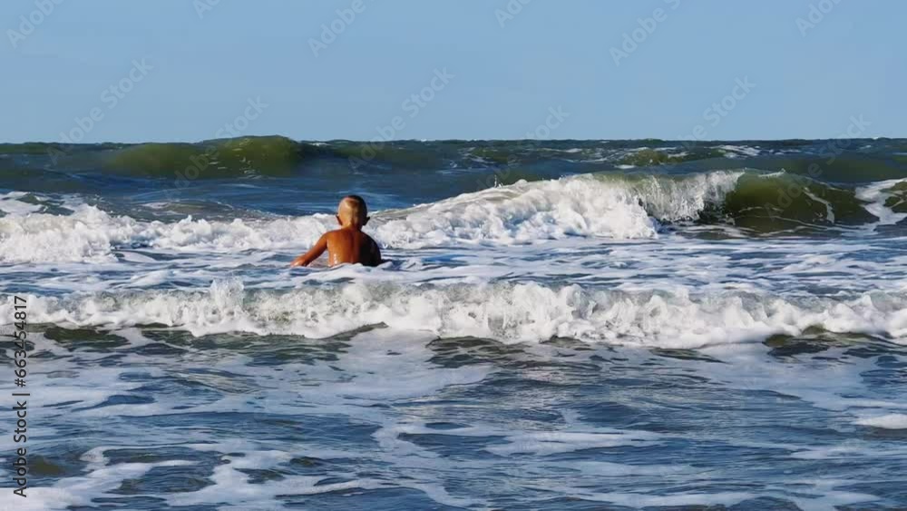 A child swims in the Sea of Azov. A boy jumps into the sea waves from ...