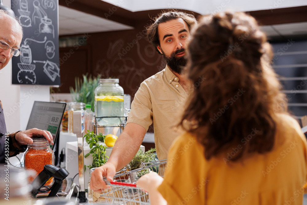 Green living couple at zero waste supermarket checkout counter with ...