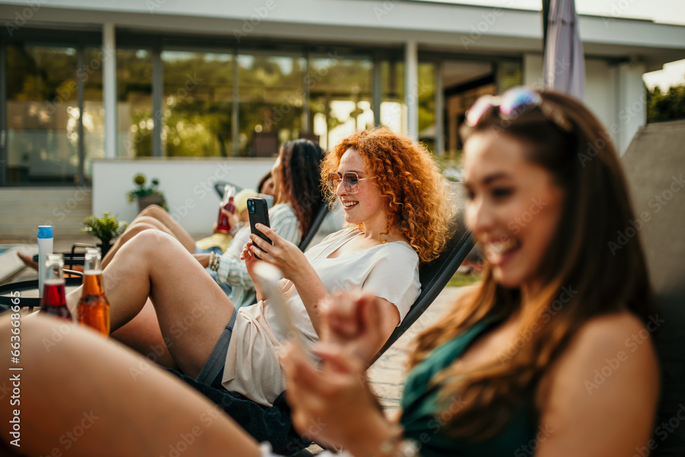 A group of friends chilling out by the pool in a house yard. They're ...
