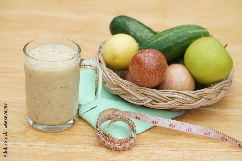 Glass of smoothie mixed fruits, basket of fresh fruits and measuring ...