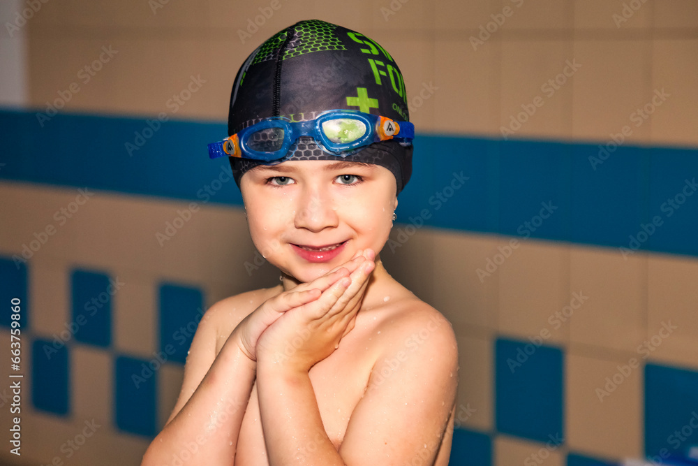 Portrait of child swimmer 5 year old in swim goggles and hat posing in ...