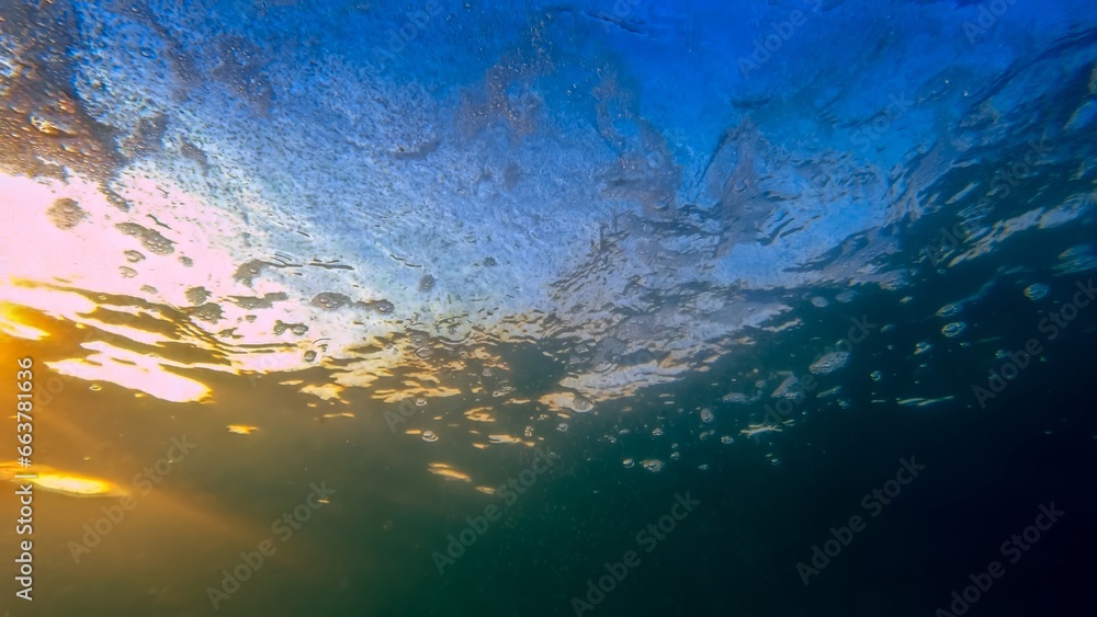 Sunset sun rays shining through clear sea water. Underwater shot from ...