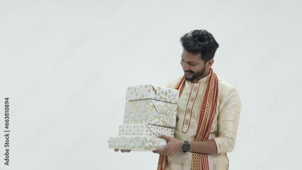 young Indian man showing our some diwali gifts and smiling front of ...