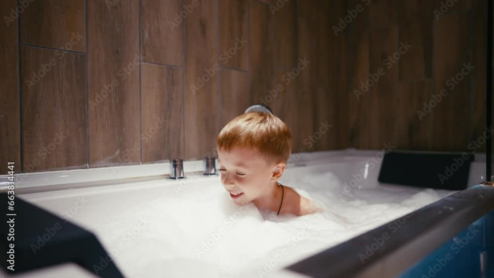 Happy little boy swimming in the bathroom. Kid bathing in a bath full ...
