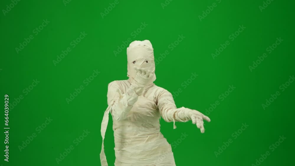 Scary mummy wrapped in bandages dancing the Macarena dance. Green ...