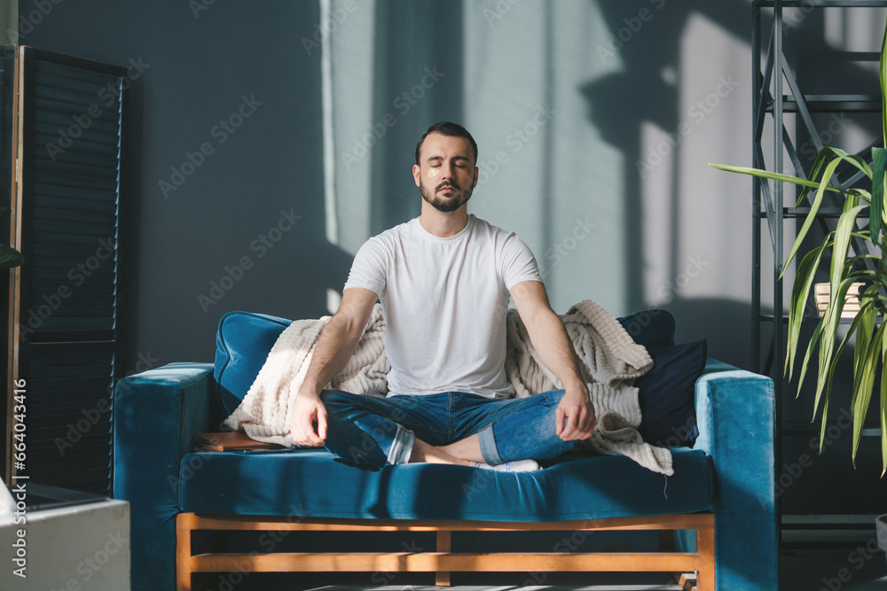 Full length view of a relaxed man sitting in his room on a soft sofa ...