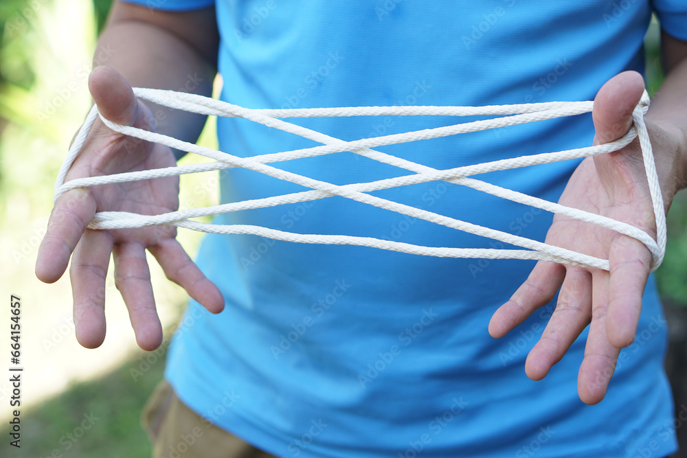 Closeup man hands is playing rope which called cats cradle game ...