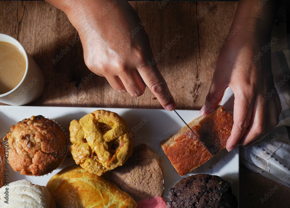 Woman's hand taking a piece of Mexican sweet bread from a white plate ...