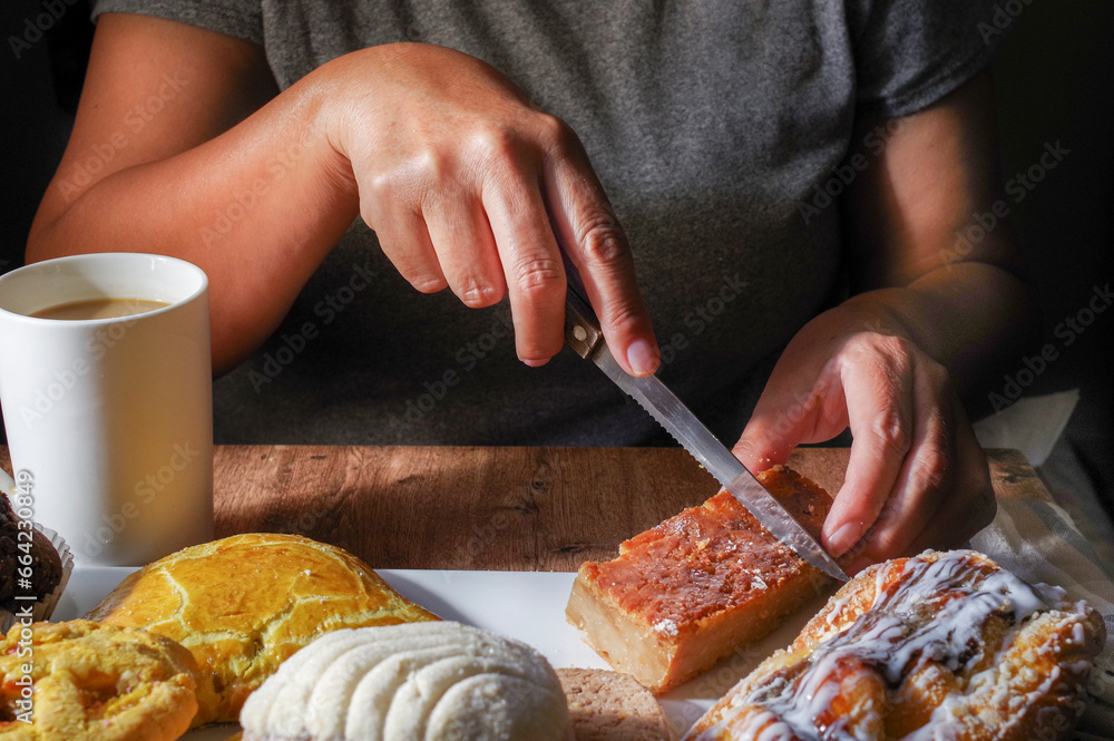 Woman's hand taking a piece of Mexican sweet bread from a white plate ...