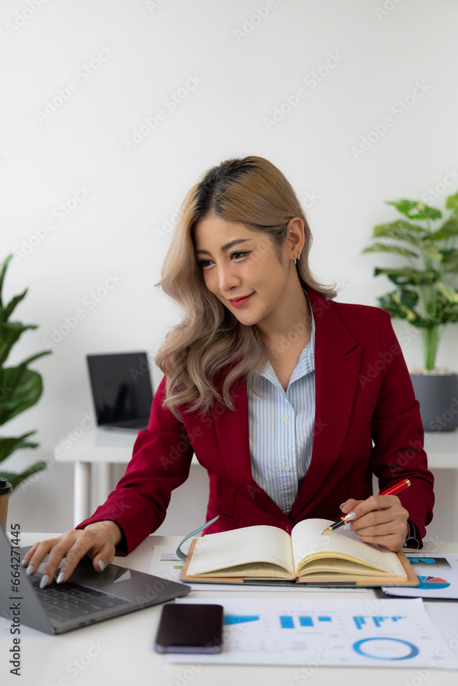 Asian female financial analyst or accountant uses laptop to work on ...