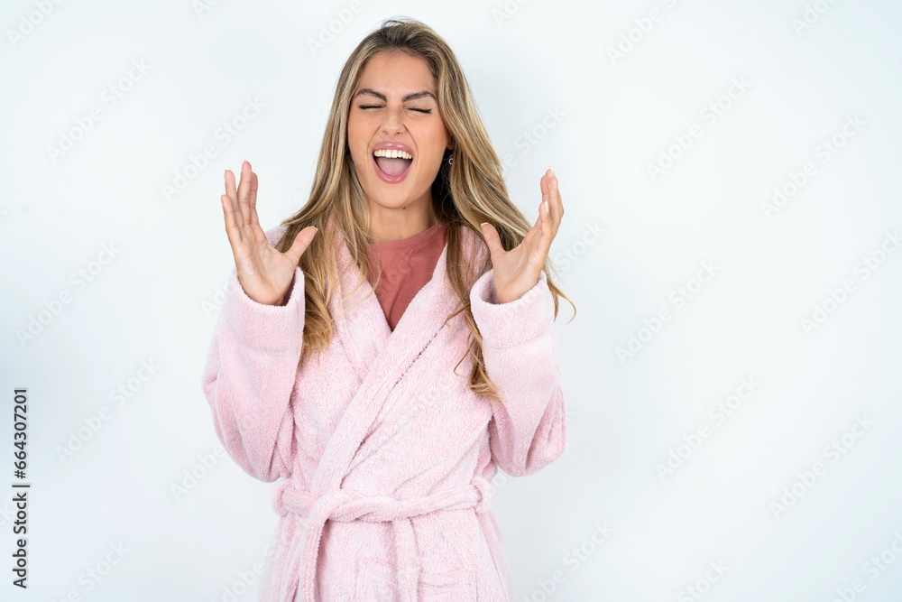 Crazy outraged young beautiful woman standing over white studio ...