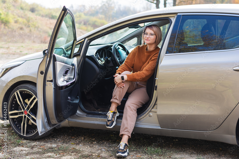 Smiling beautiful woman with short haircut sitting in car. Learning to ...