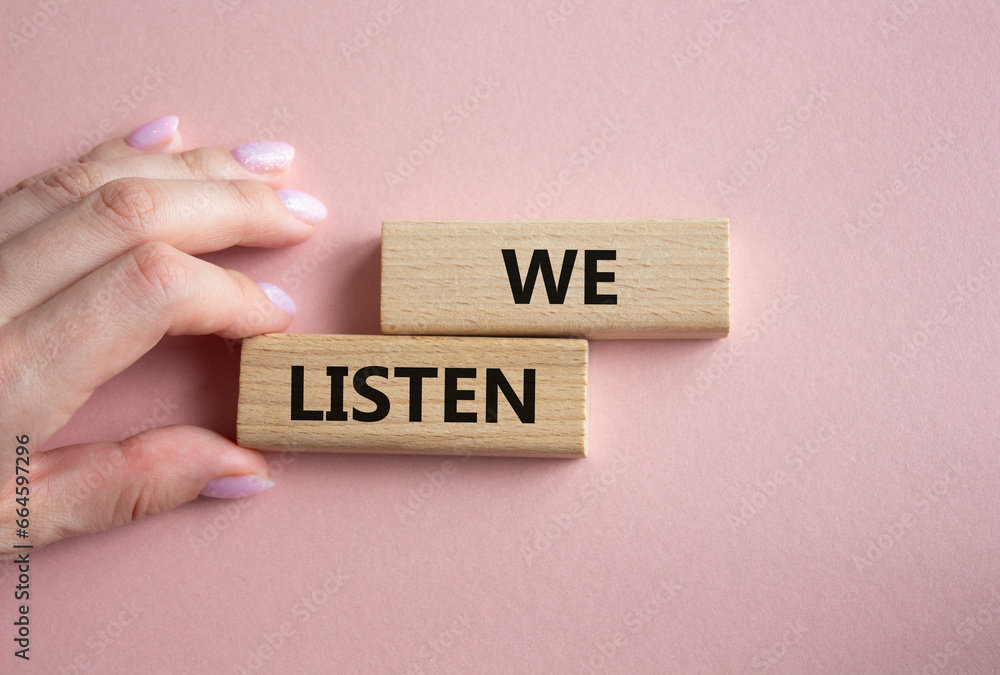 We listen symbol. Wooden blocks with words We listen. Businessman hand ...