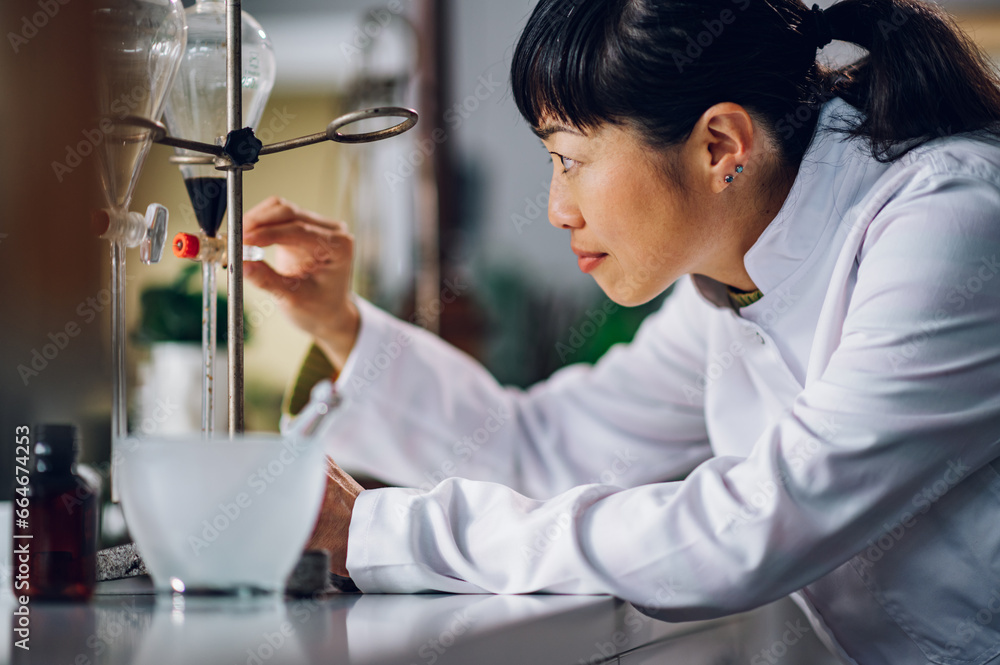 Side view of a Japanese pharmacy technician working on drug making in a ...