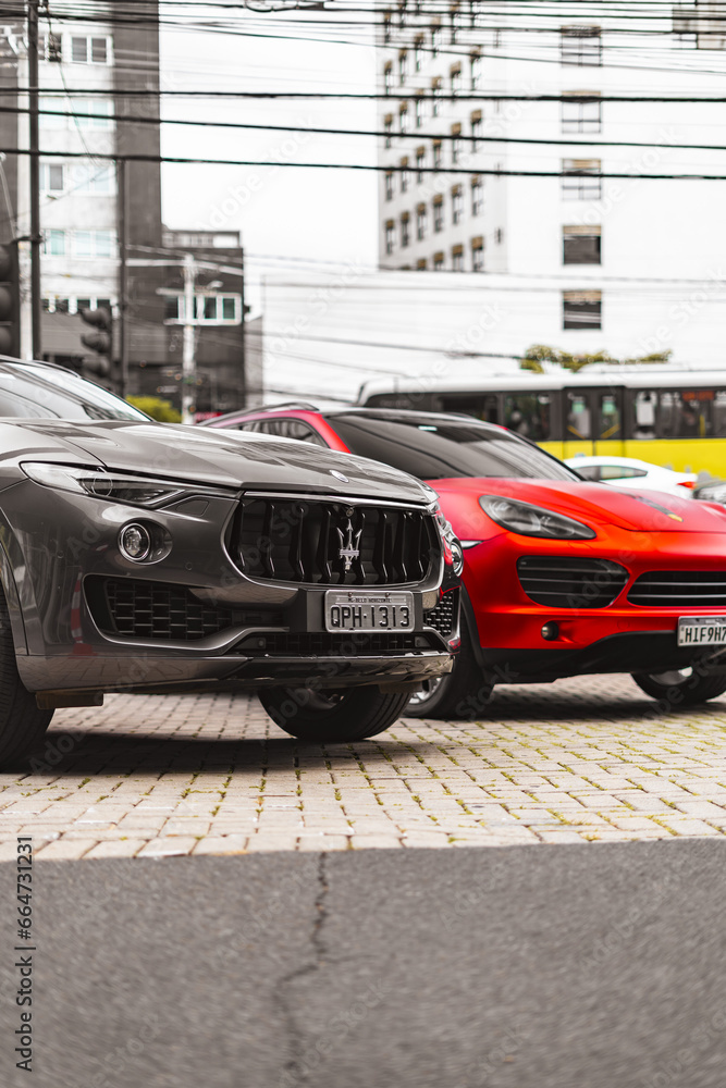 Grey Maserati Levante and Red Porsche Cayenne parked side by side, low ...