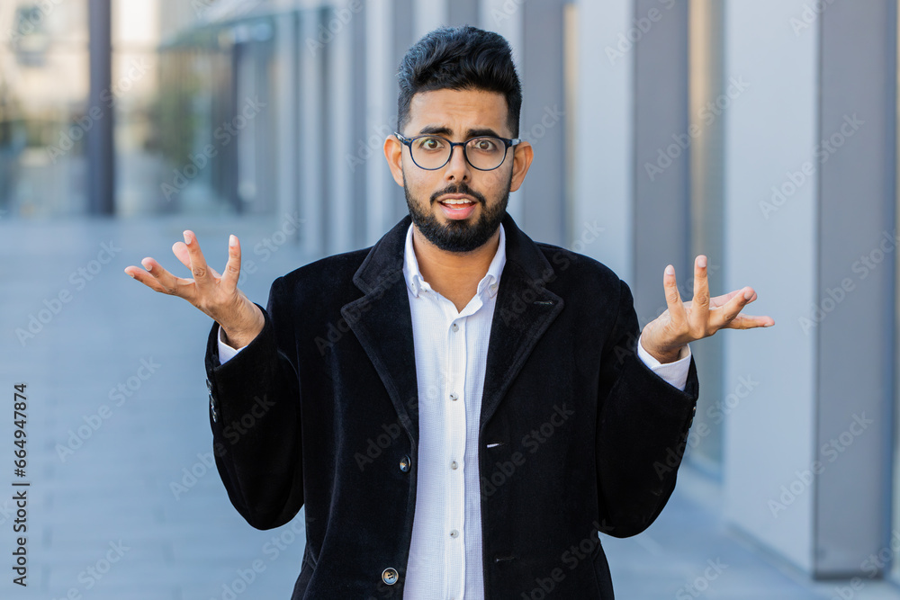What. Why. Surprised frustrated Indian businessman raising hands asking ...