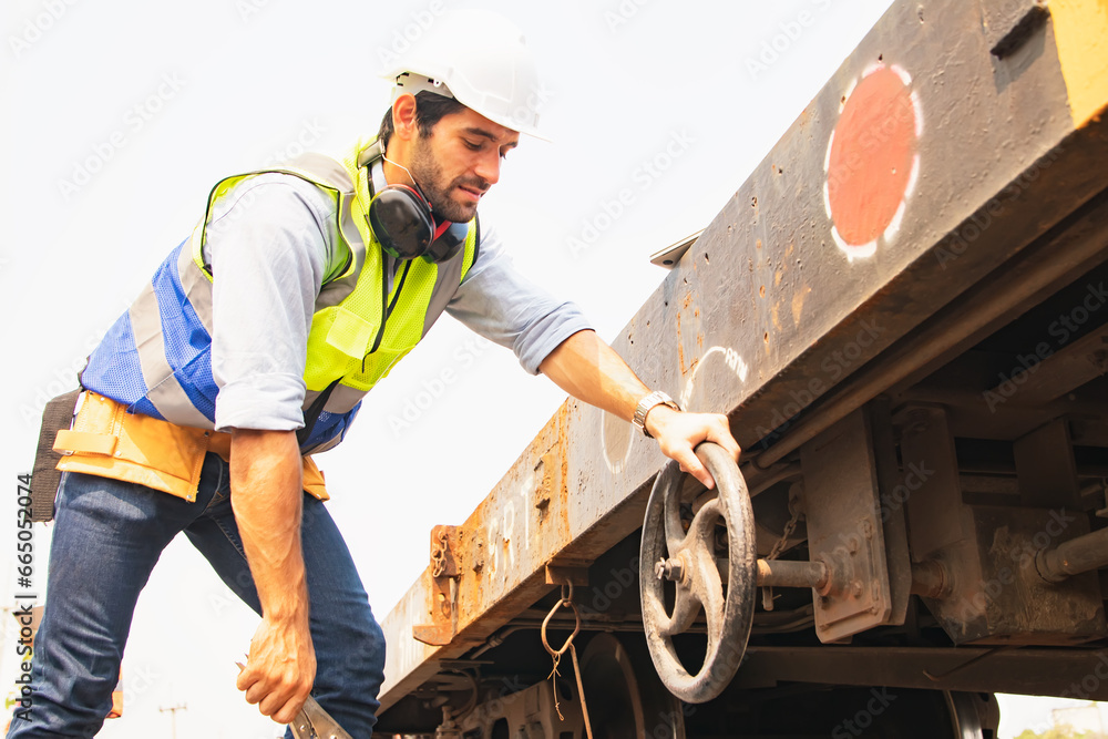 Handsome young railway technician wearing hard vest sits and analyzes ...